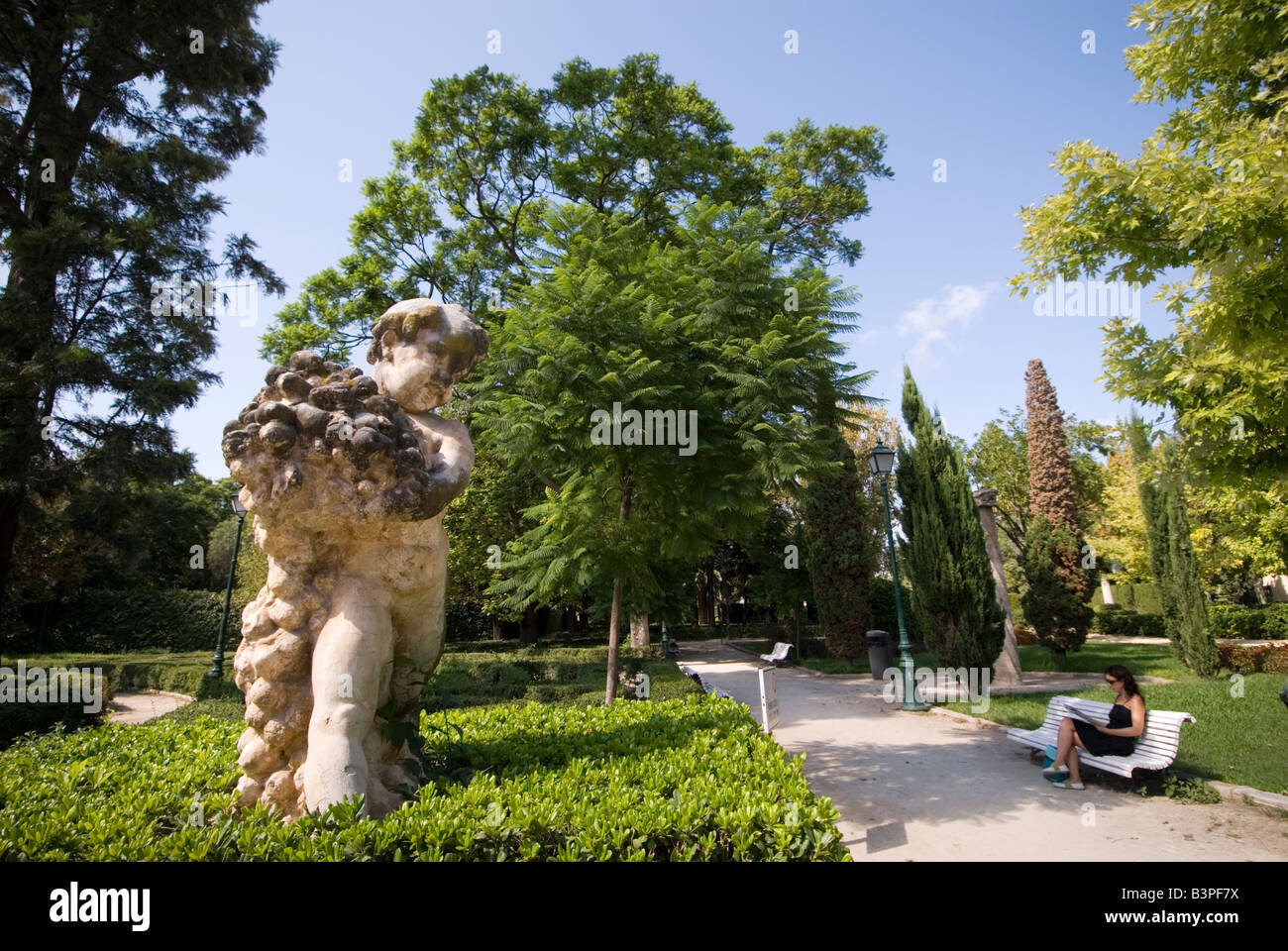 Woman sitting on park bench in Jardin del Real Viveros in Valencia ...
