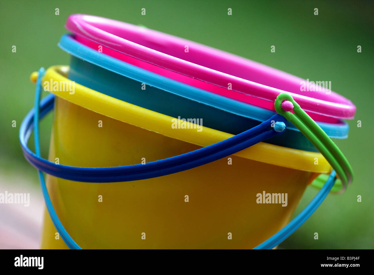 Coloured childrens buckets against green background Stock Photo - Alamy