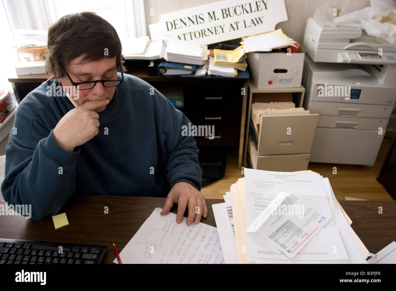 white male sitting at messy desk and computer with papers around him ...