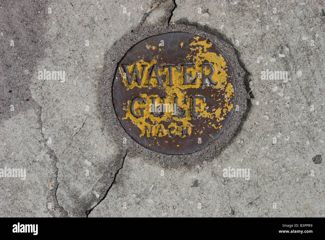 Rusty water line marker in sidewalk which says "Water Gulf" in ...