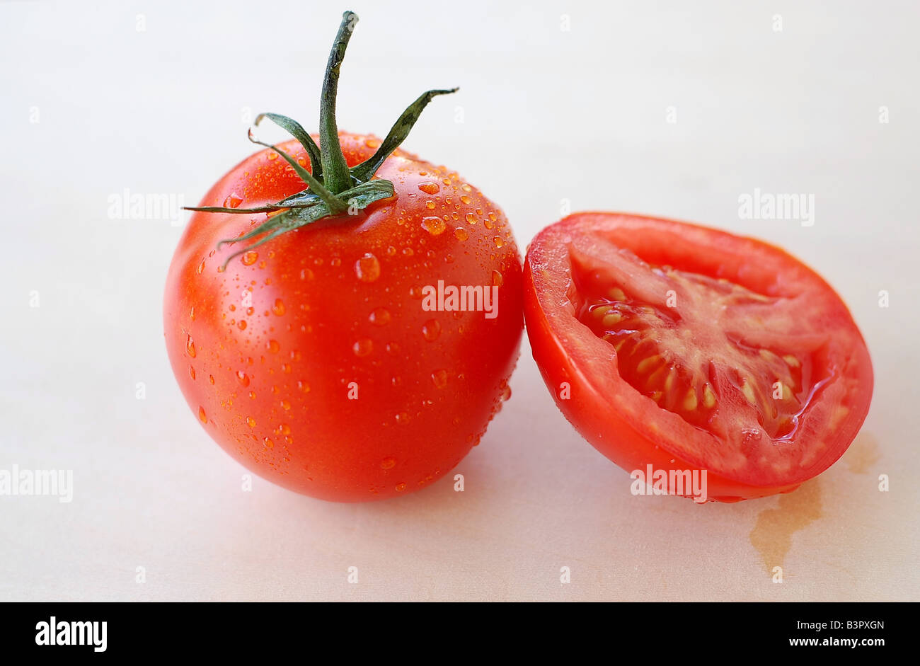 Vine ripened tomato along side a sliced tomato on cutting board Stock ...