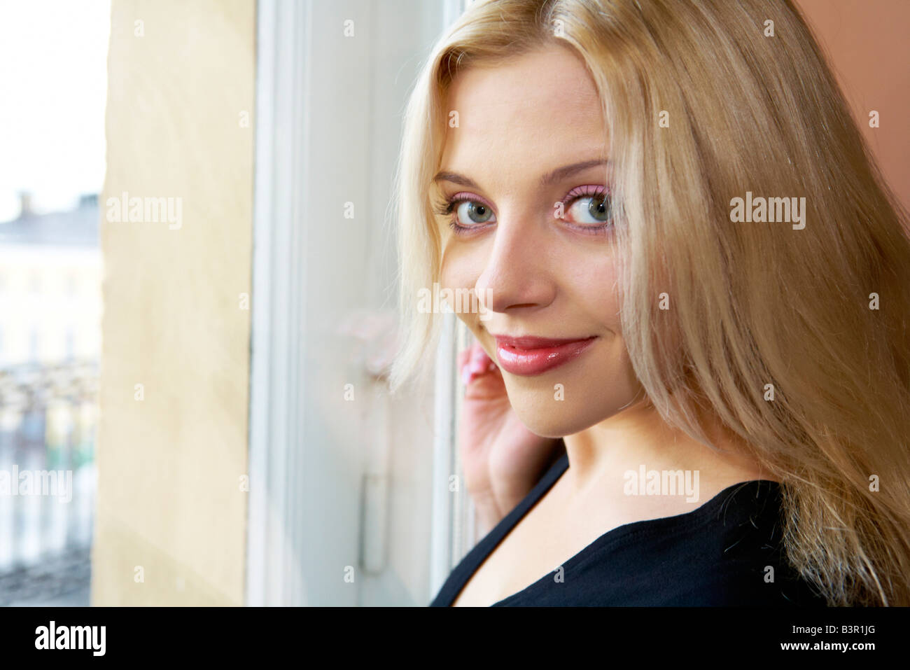 Young woman beside window looking at camera Stock Photo - Alamy