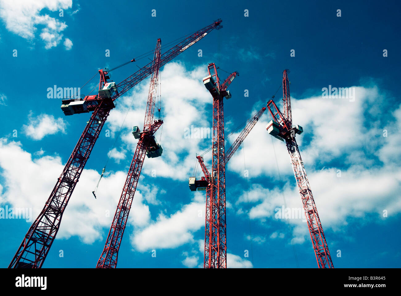 Five tower cranes looking up towards sky Stock Photo - Alamy