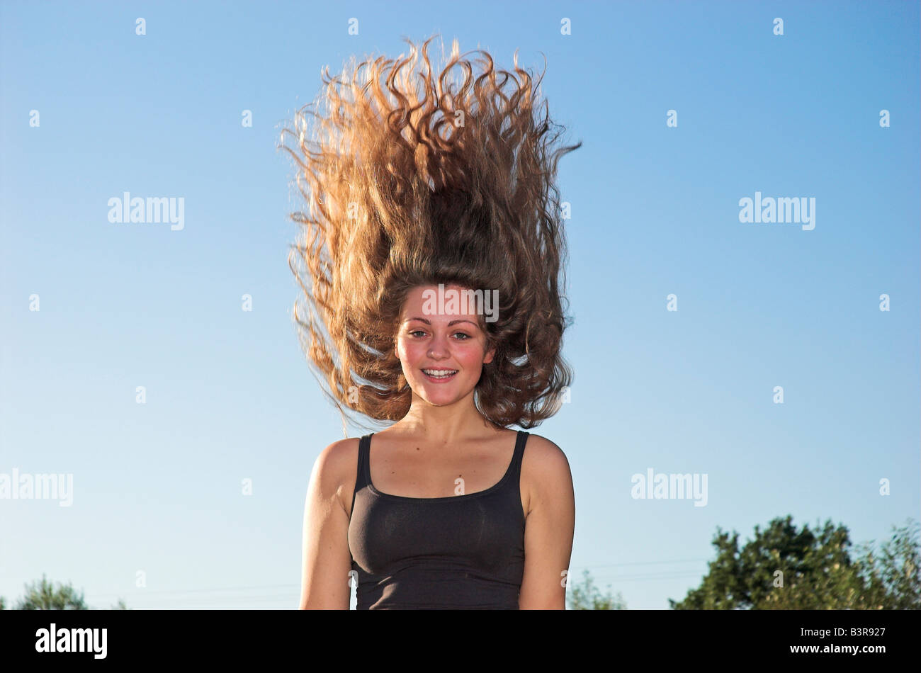 Smiling teenage girl 16 18 with long hair tossing head back portrait ...
