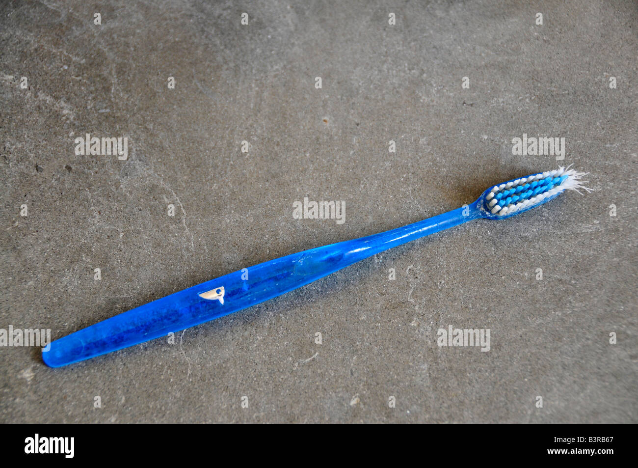 blue used toothbrush against a grey stone background Stock Photo - Alamy