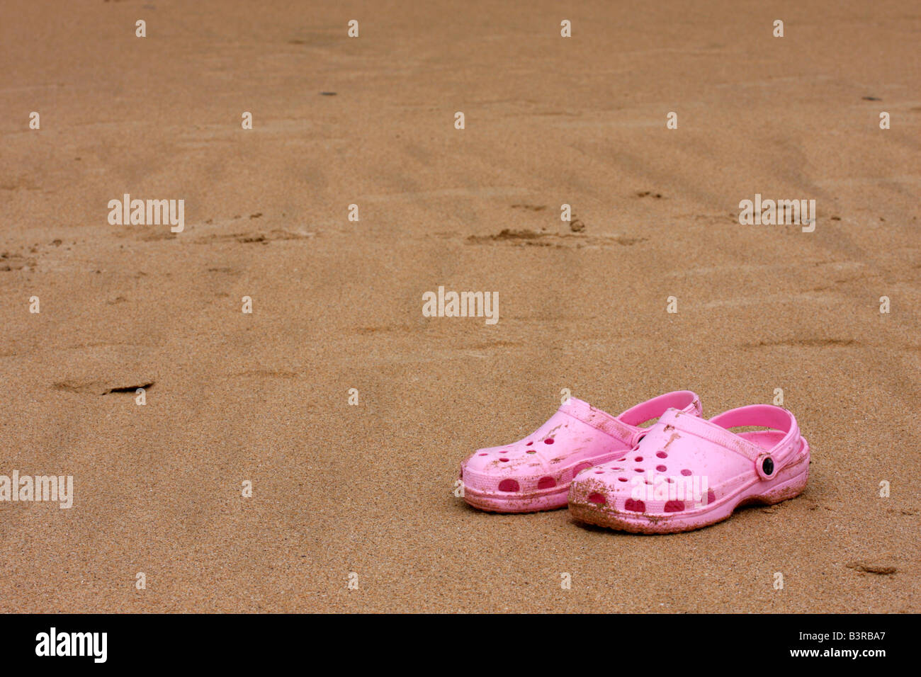 Pair of Crock type shoes on a sandy beach Stock Photo - Alamy