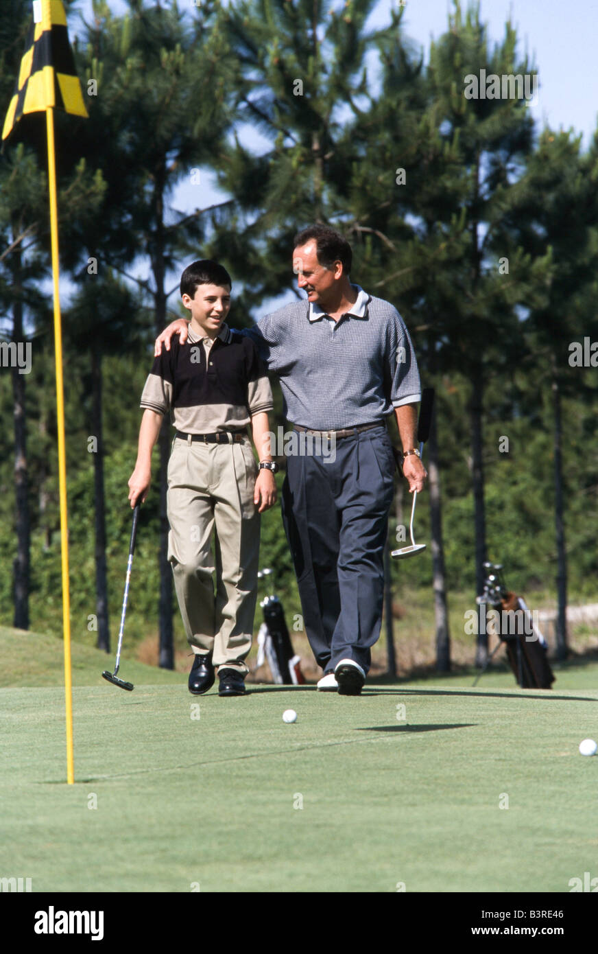 Father and teen son playing golf together, father teaching golf skills ...