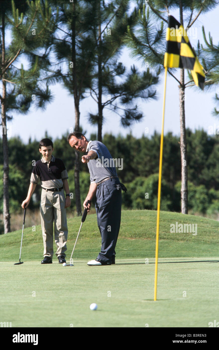 Father and teen son playing golf together, father teaching golf skills ...