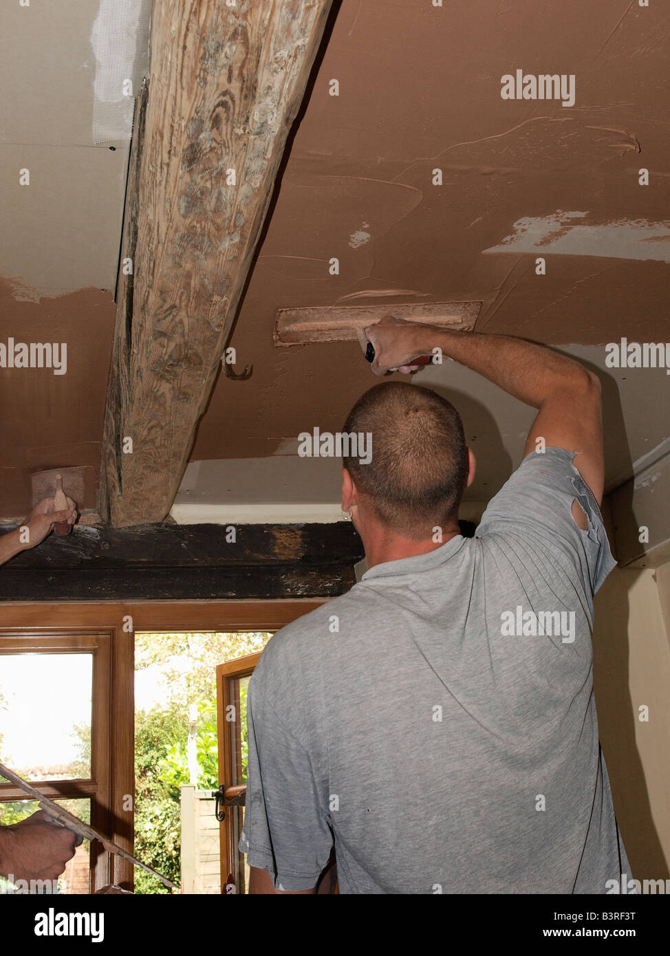 PLASTERER USING TROWEL TO APPLY FIRST COAT OF MIXED PLASTER TO ...