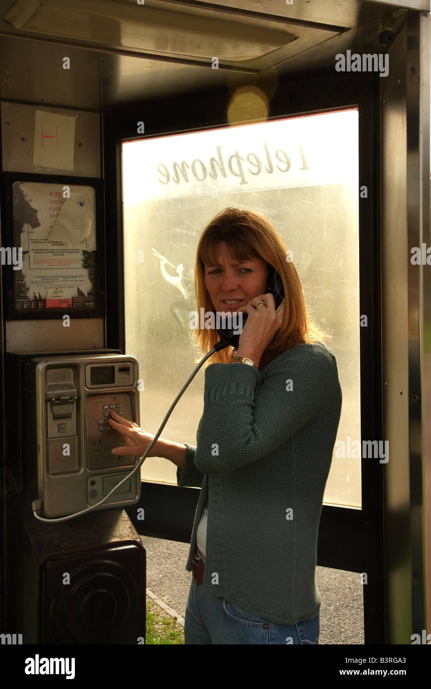 Woman using callbox telephoning from a payphone which BT tend to remove ...