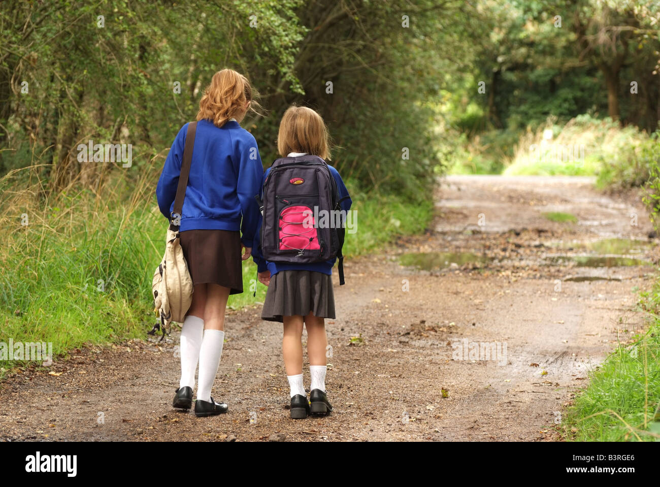 Schoolgirls in uniform walking to school along a lonely country lane in ...