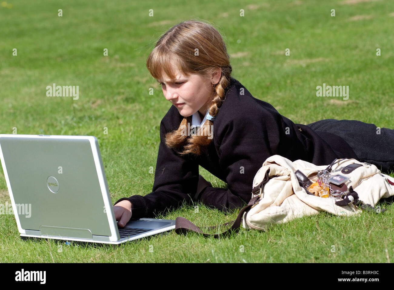 Schoolgirl laying on grass using a laptop computer Stock Photo - Alamy
