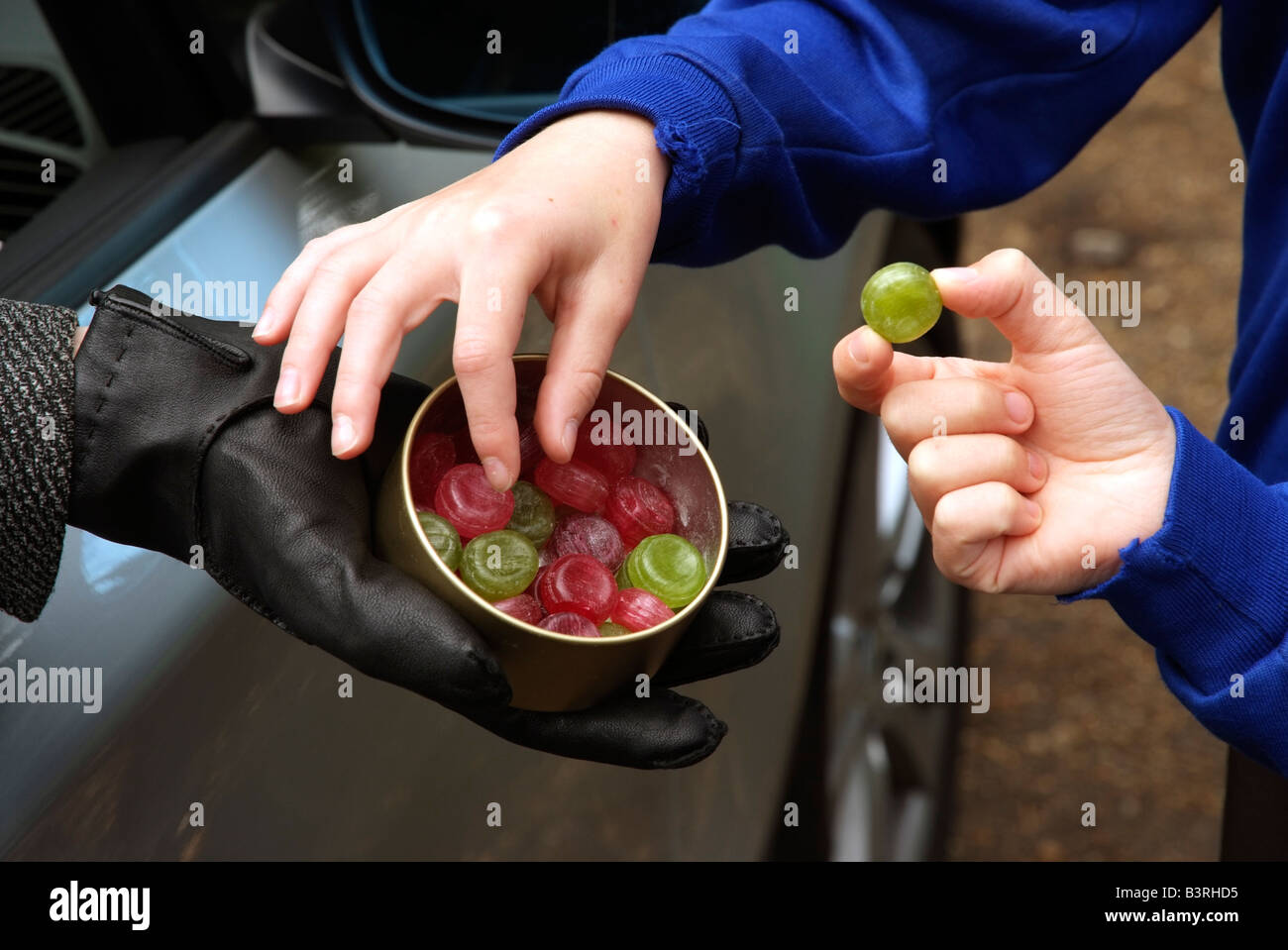 Young girls hands taking sweets from a stranger motorist wearing a ...