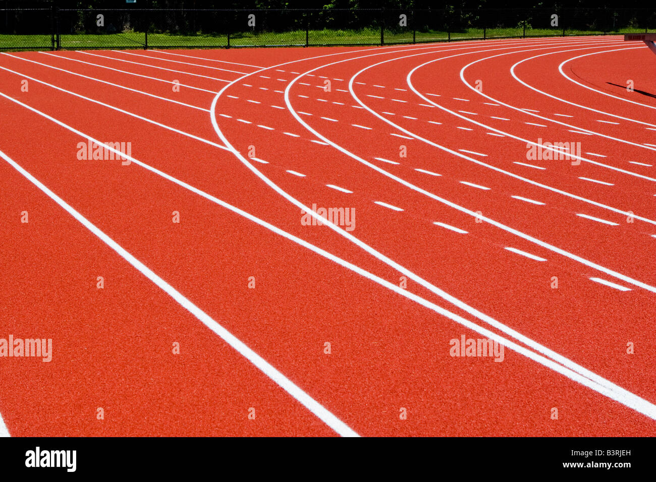Red orange running track with white straight and curving lane lines ...