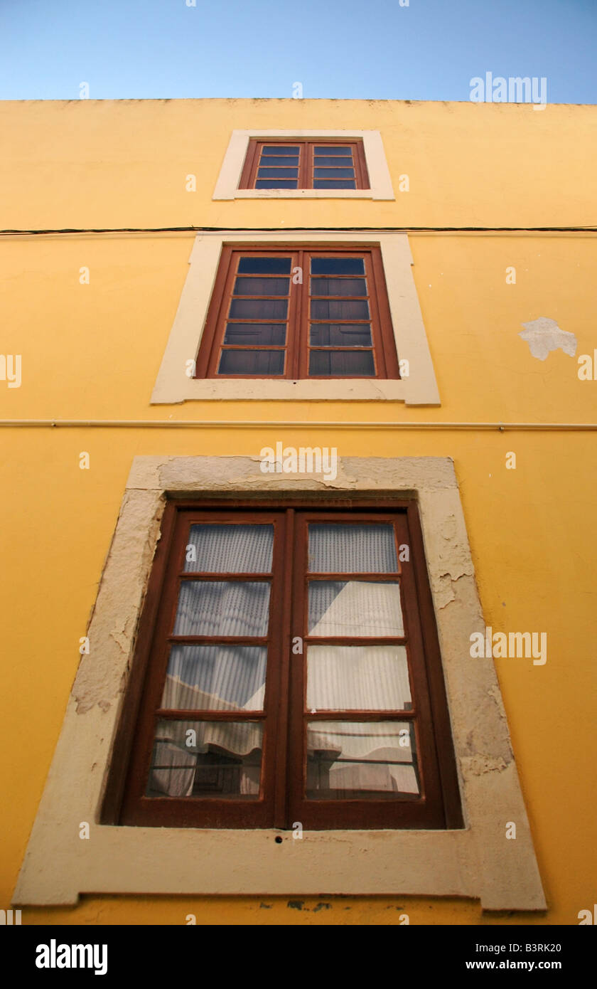 Looking up at the side of a three storied building and its windows ...