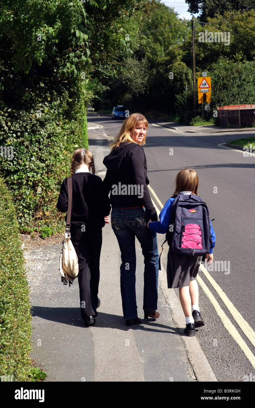 Mother and children walking to school along a pavement Stock Photo - Alamy