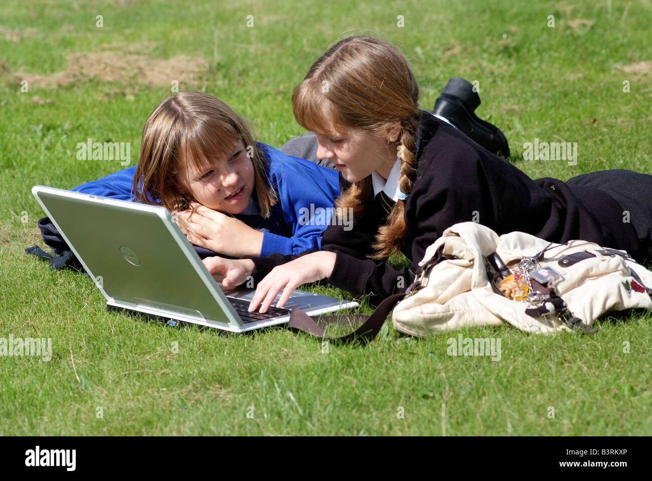 Two schoolgirls laying on grass using a laptop computer Stock Photo - Alamy