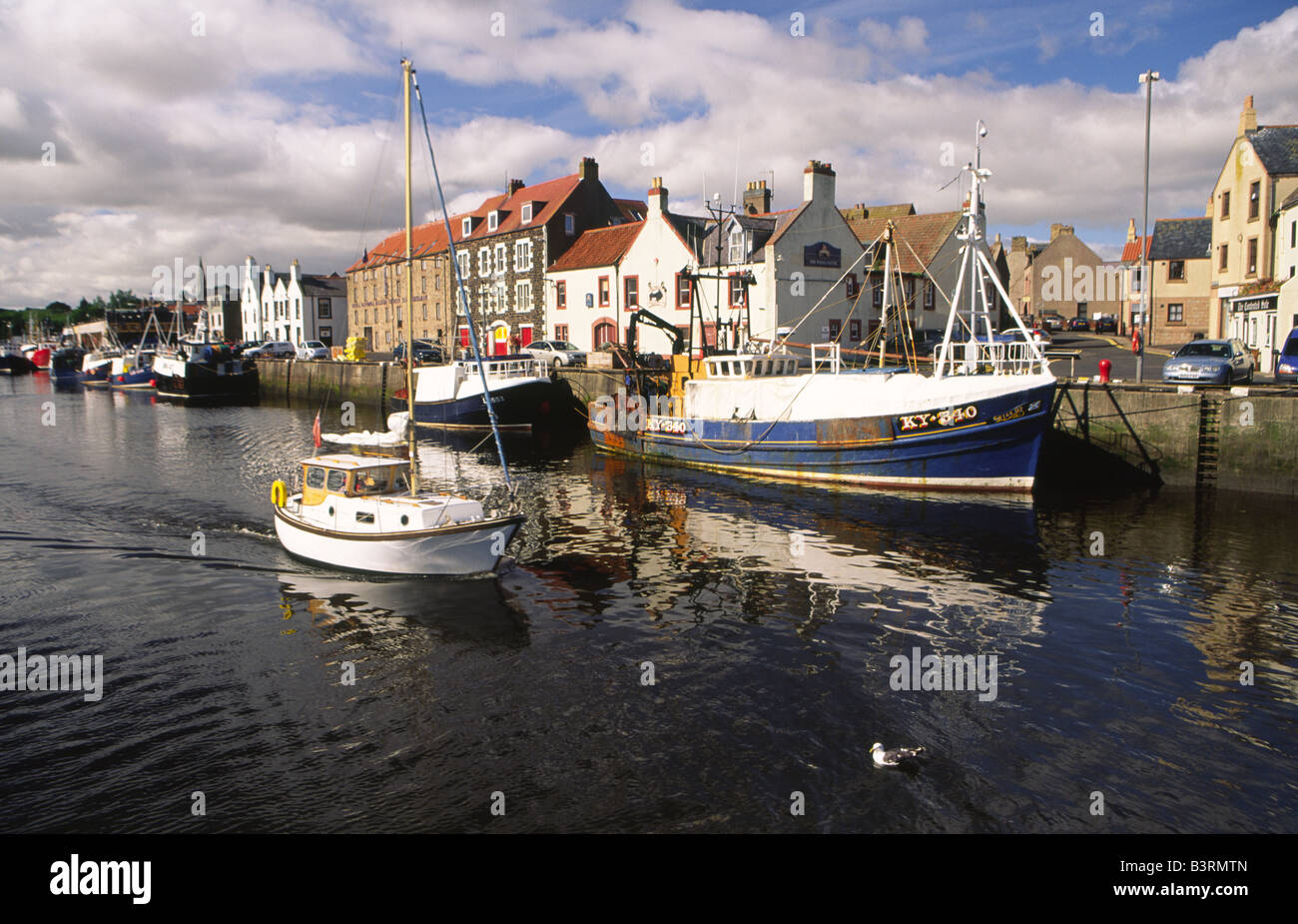 Small yacht leaving a picturesque Eyemouth Harbour fishing boats and ...