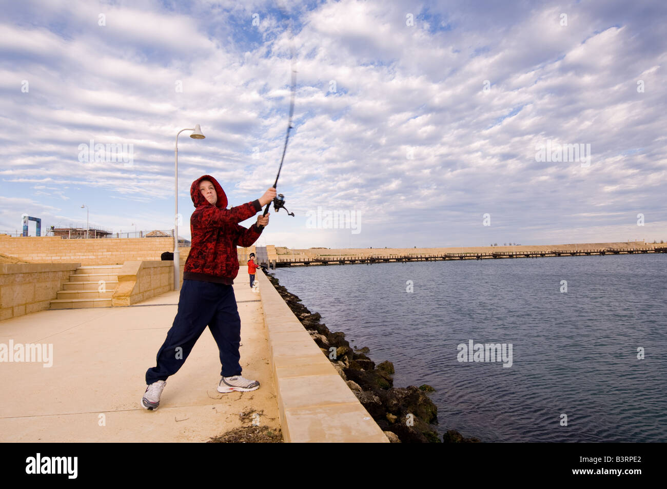 Two brothers fishing in early morning light in a boat harbor set ...