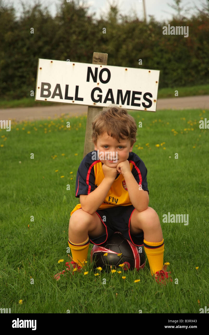 Small boy and football wearing soccer team kit stands with a no ball ...