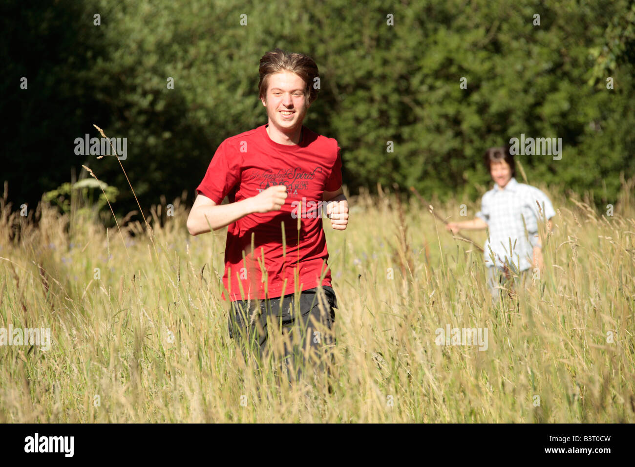 teenage boys running through high grass Stock Photo - Alamy
