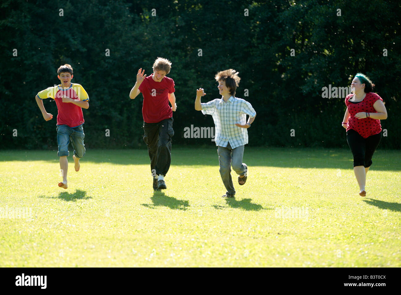 four teenagers running across lawn Stock Photo - Alamy