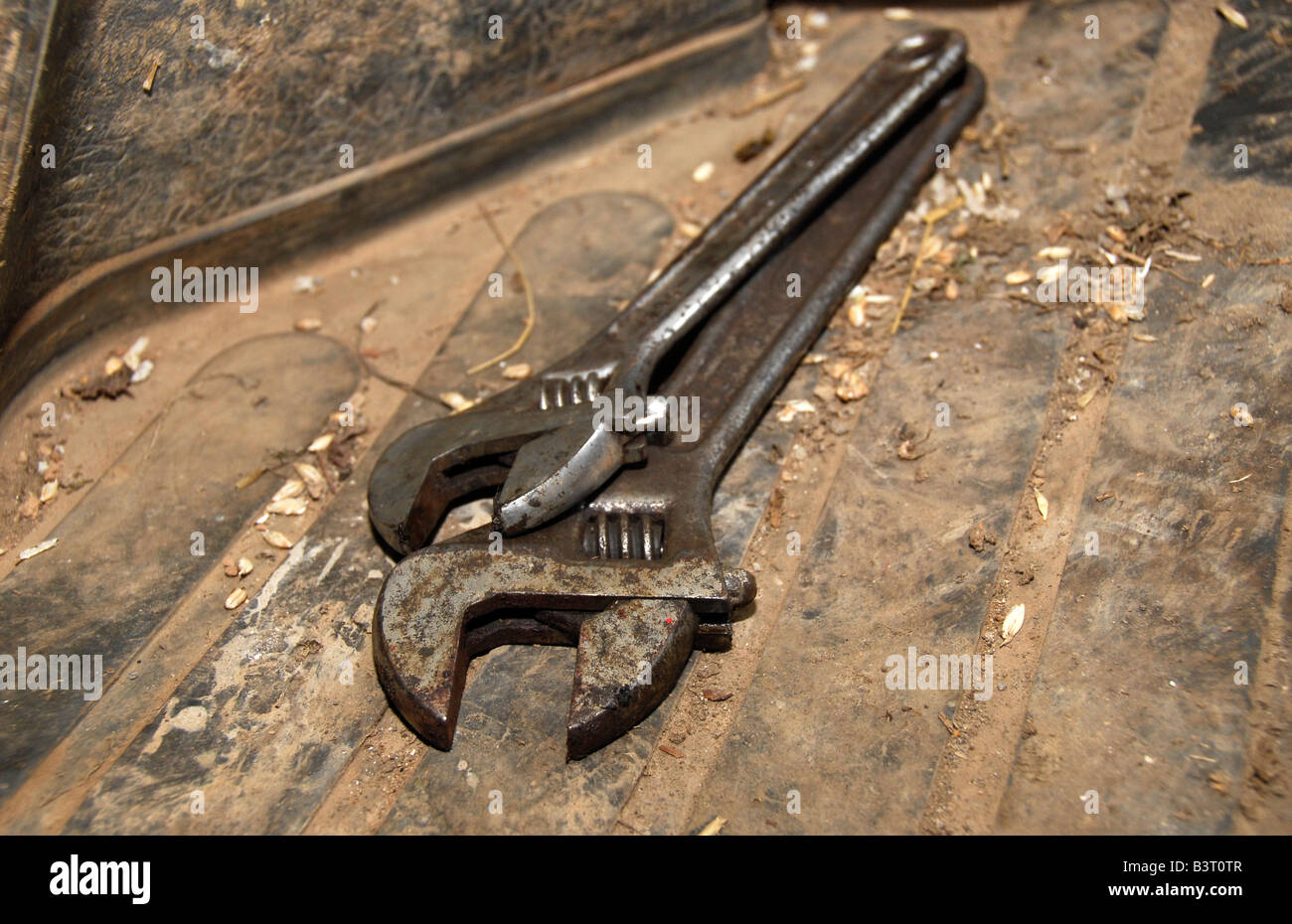 Two well used rusty adjustable spanners (wrenches) lying on a dusty ...