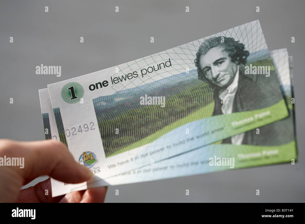 A hand holds Lewes pound notes, featuring Thomas Paine Stock Photo - Alamy