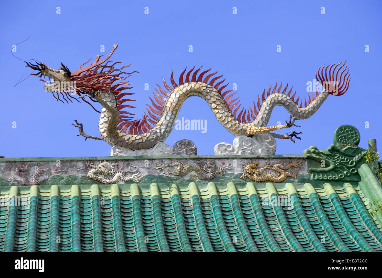 Eastern mythological red and green spiny dragon along green ridge tiles ...