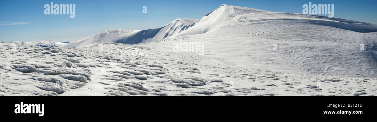 Winter mountains ridge with overhang snow caps and snowboard tracks on ...