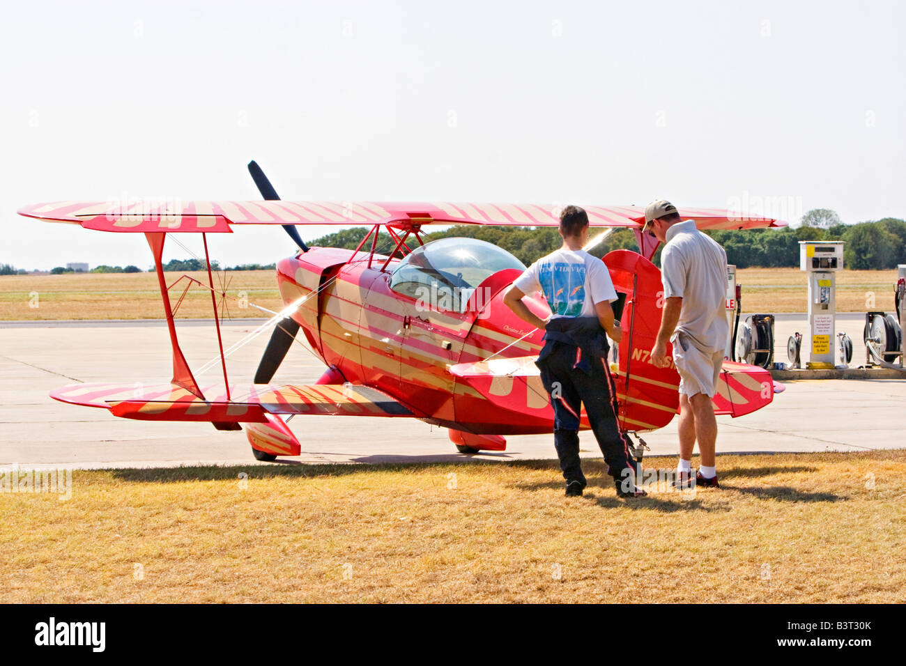 Two pilots talking with each other beside acrobatic biplane airplane ...