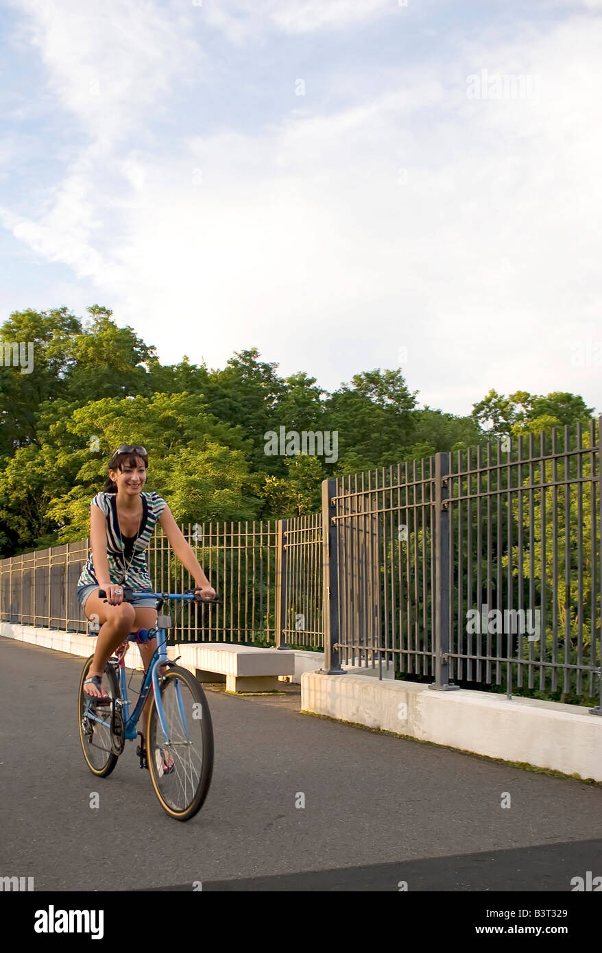 A young woman riding her bicycle across the bridge Stock Photo - Alamy