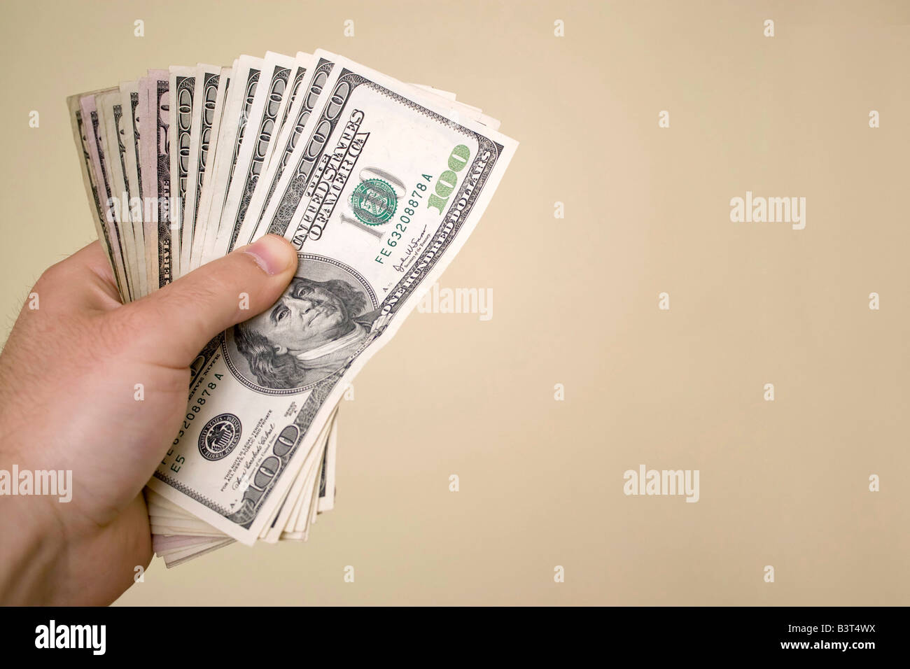 A handful of cash isolated over a gold background Stock Photo - Alamy