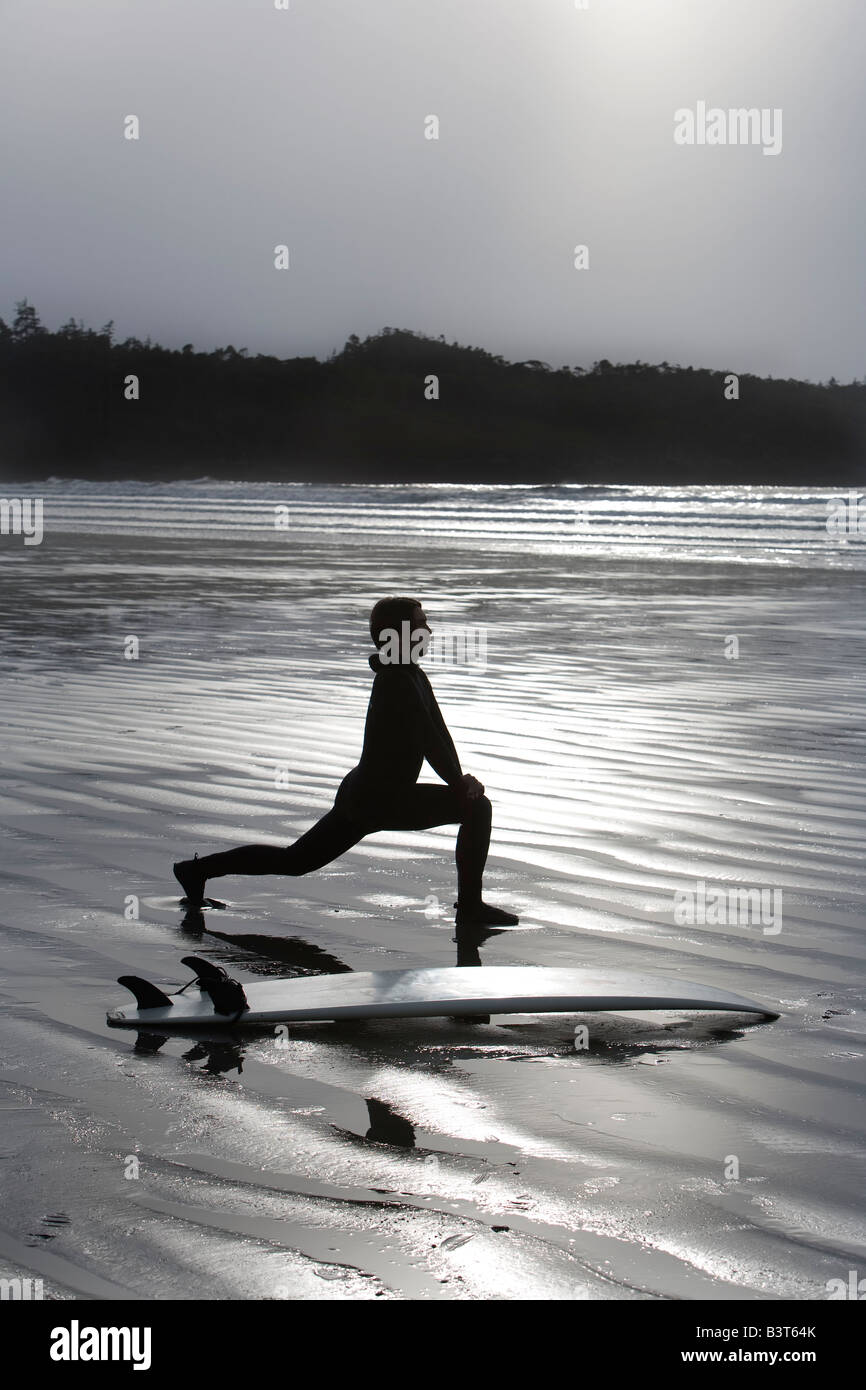 Surfer stretching on beach Stock Photo - Alamy