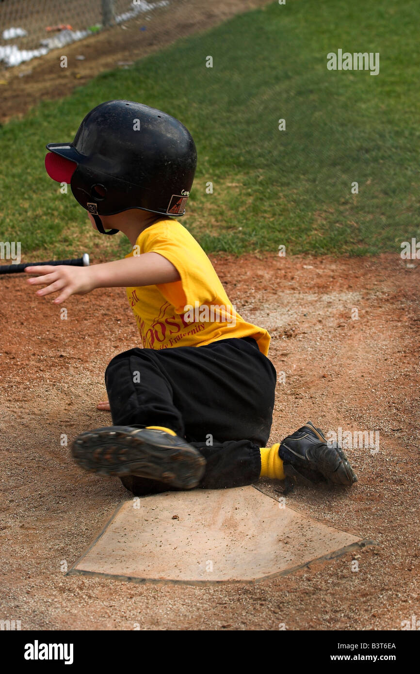 A youngster slides into home during a coach-pitch, little-league game ...