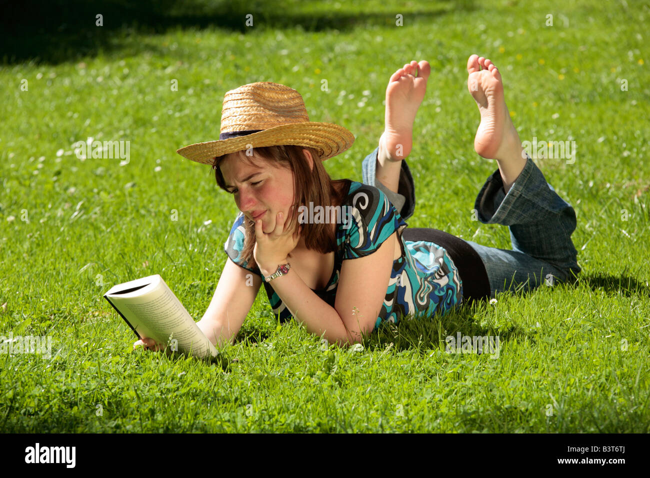 teenage girl lying on a lawn reading a book Stock Photo - Alamy