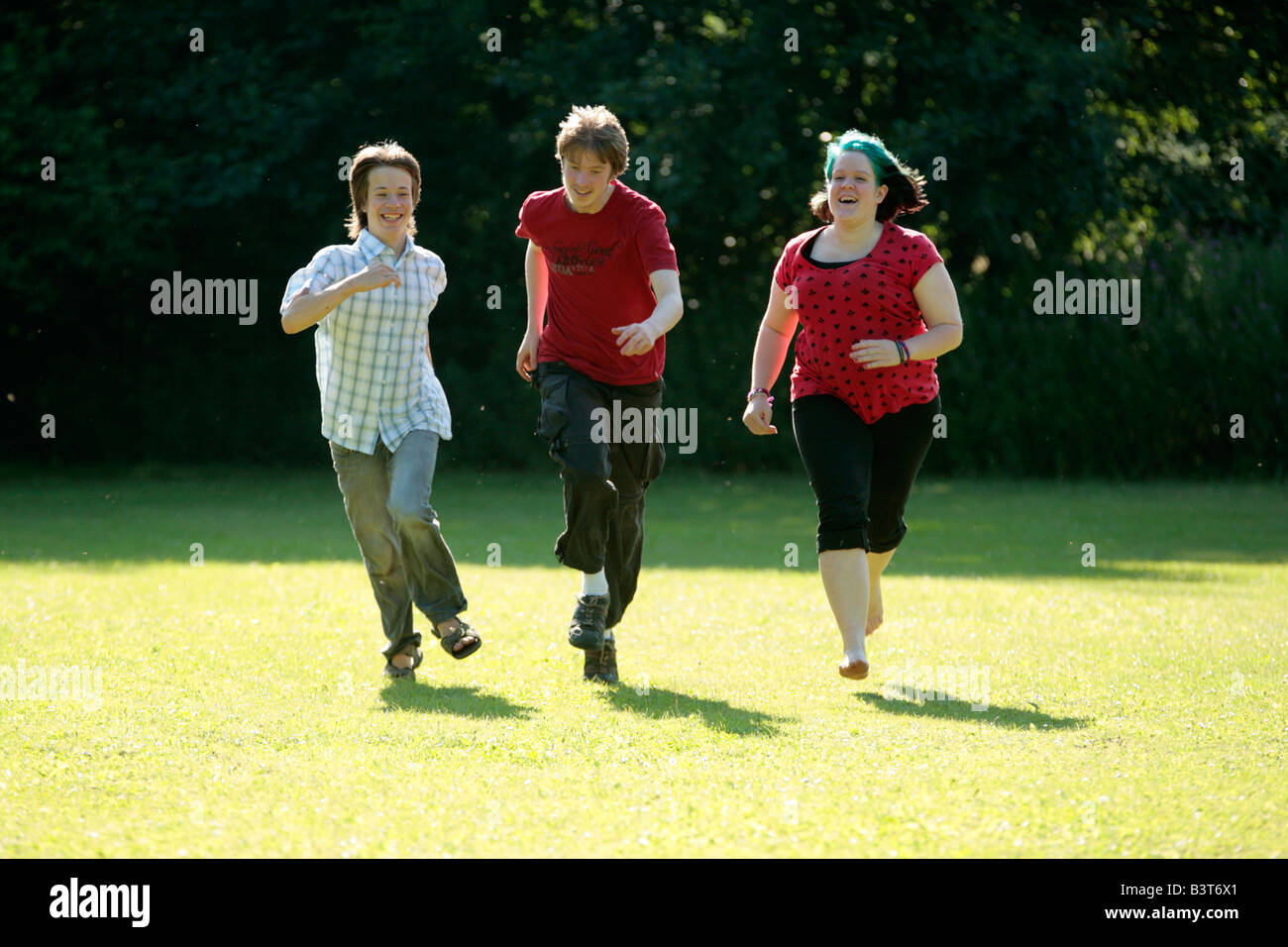 three teenagers running across lawn Stock Photo - Alamy