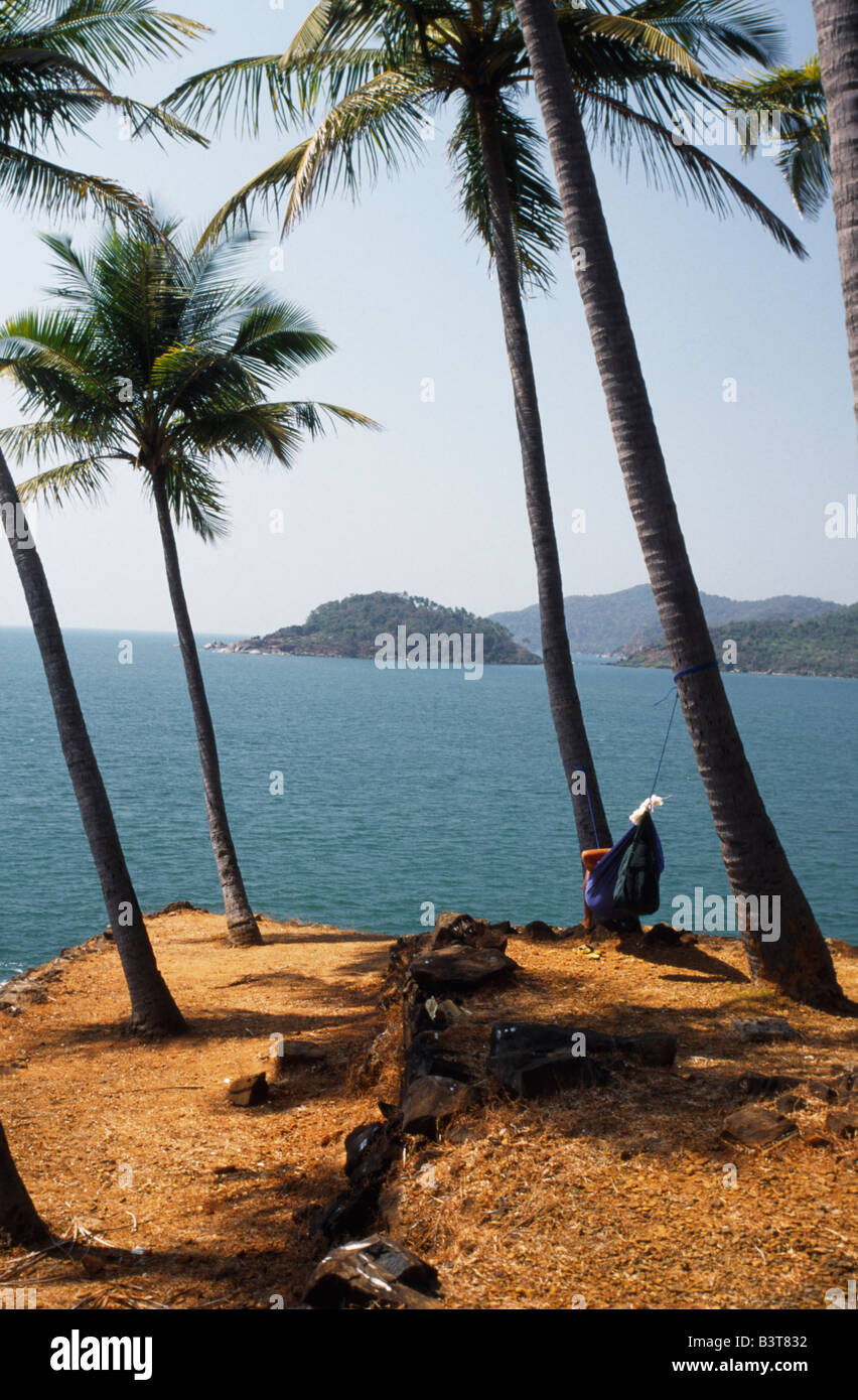 India, Goa, A tourist dozes in a hammock on a headland by Palolem Beach ...