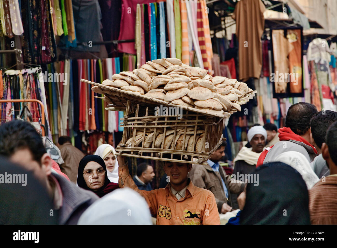 Young man carrying freshly baked bread through crowded Khan el Khalili ...