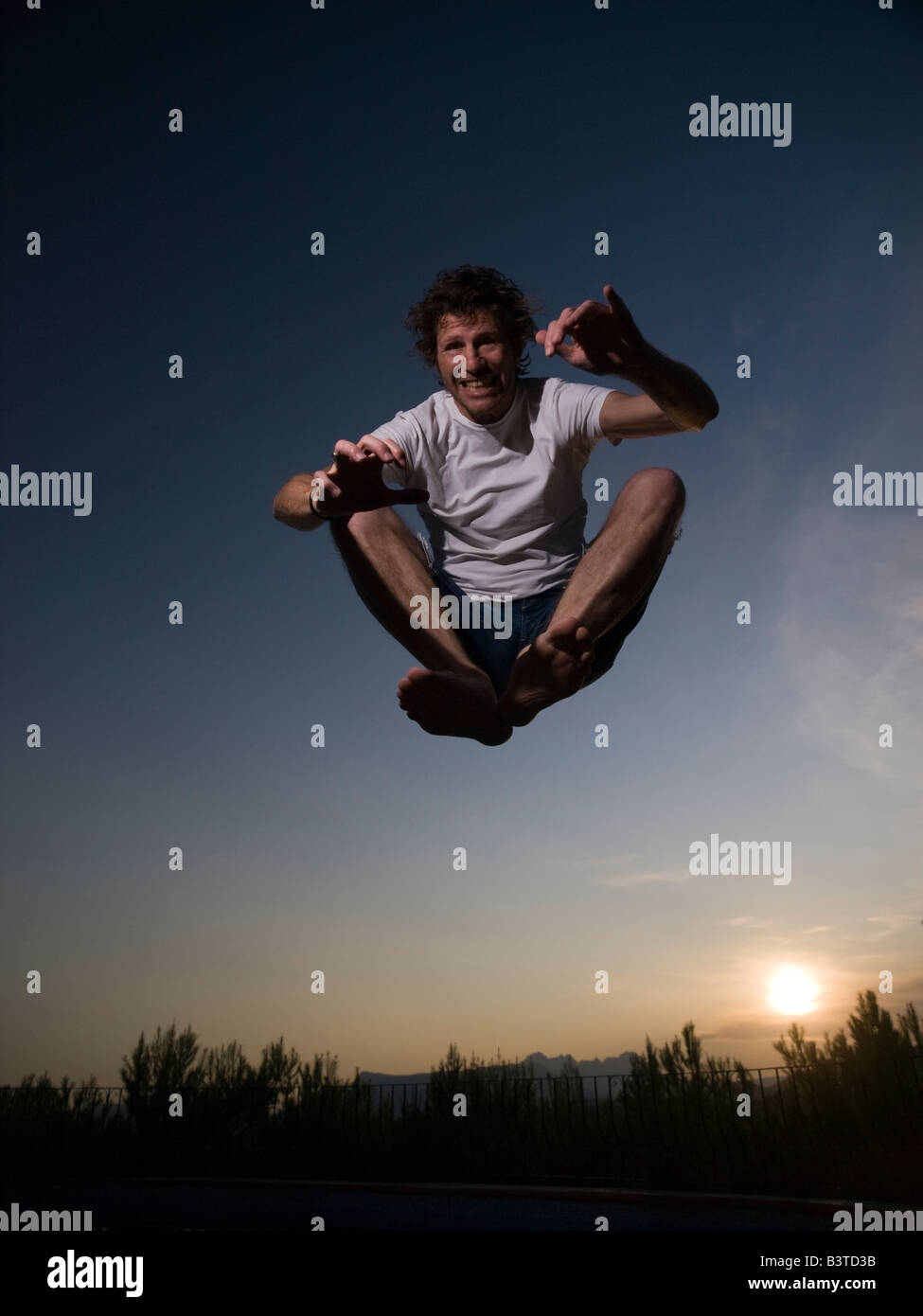 Man frozen and floating in mid air after jumping at sunset Stock Photo ...