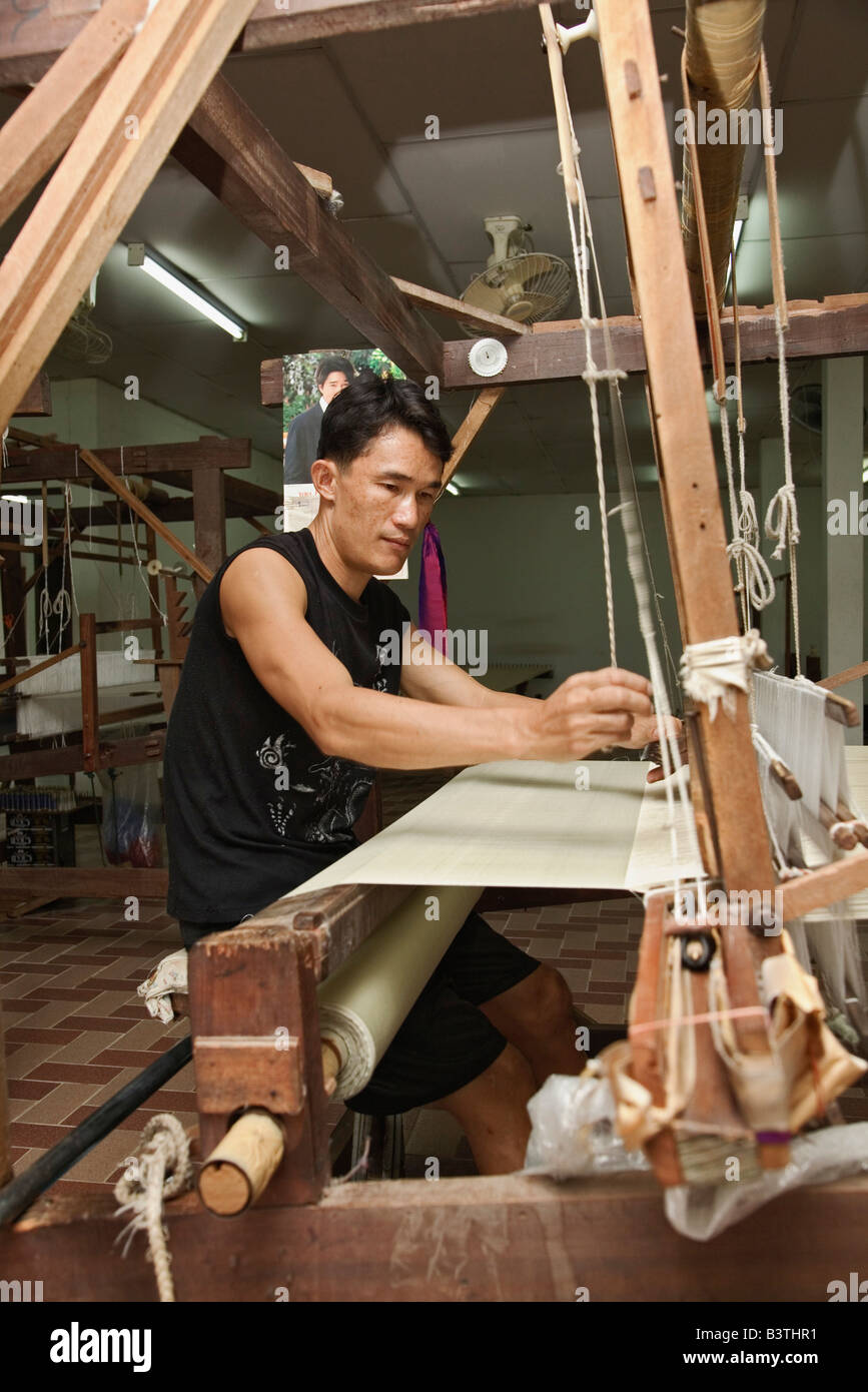 Young Thai man operating manually powered silk weaving loom in a ...
