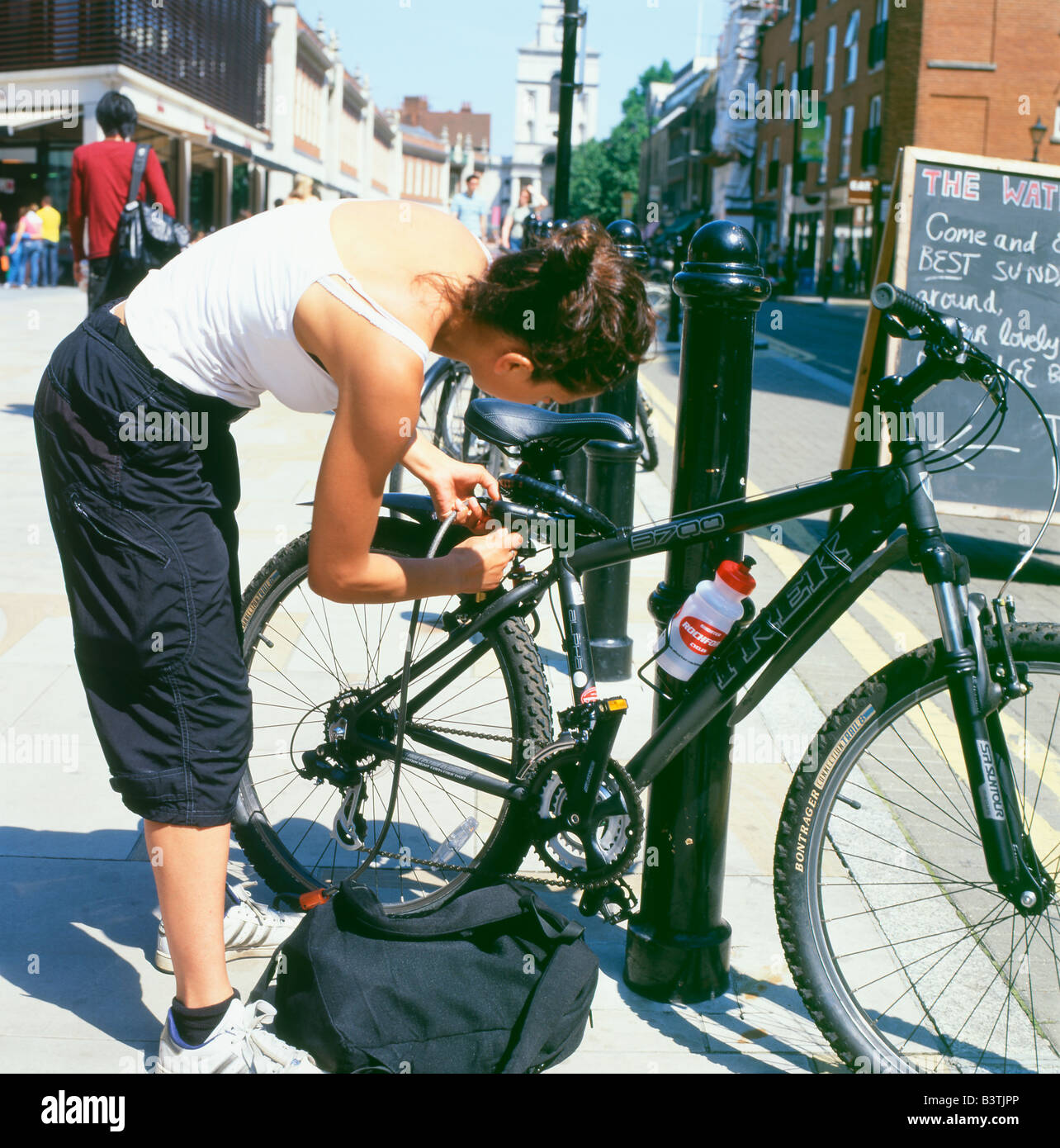 A female cyclist locking her bicycle to a hitching post in Spitalfields ...