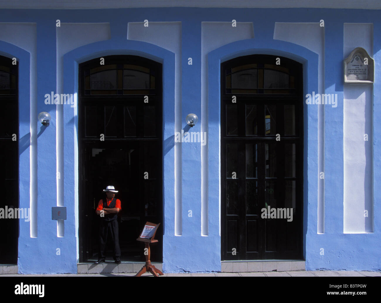 Cuba, Havana. Man standing on doorstep of blue-colored restaurant Stock ...