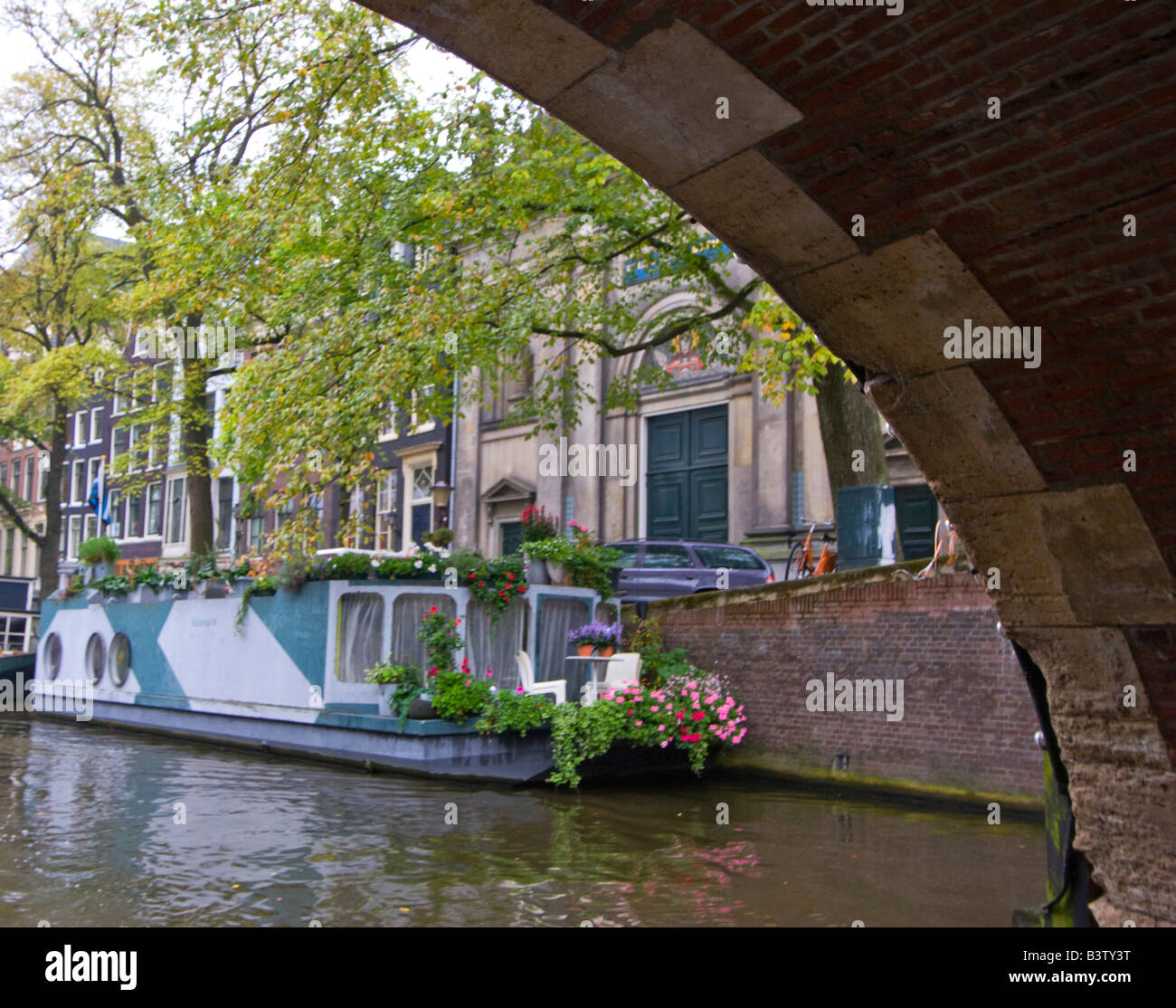 View from under a canal bridge with a colorful houseboat with flowers ...