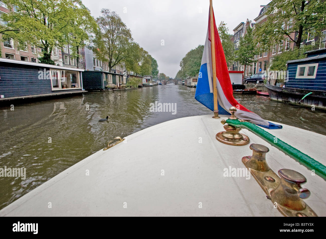 View from the front of a boat with a colorful flag, traveling a canal ...