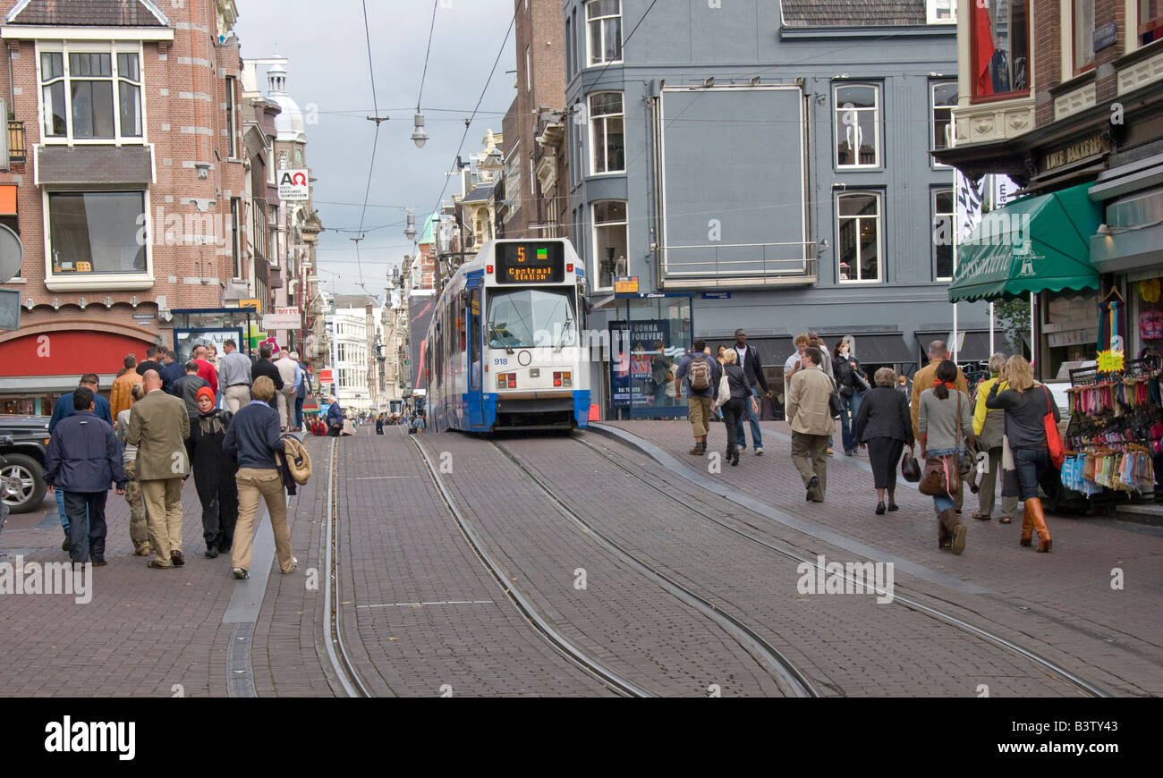 Busy Amsterdam street scene with a tram on a track and many people ...