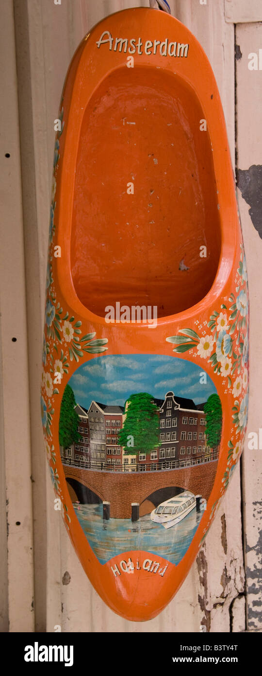 A bright orange wooden clog painted with flowers and a typical ...