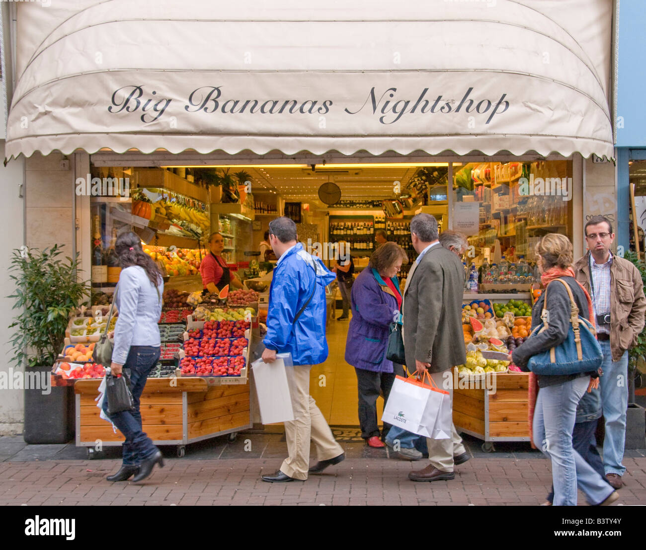 Active street scene with people looking at fresh fruit at a produce ...