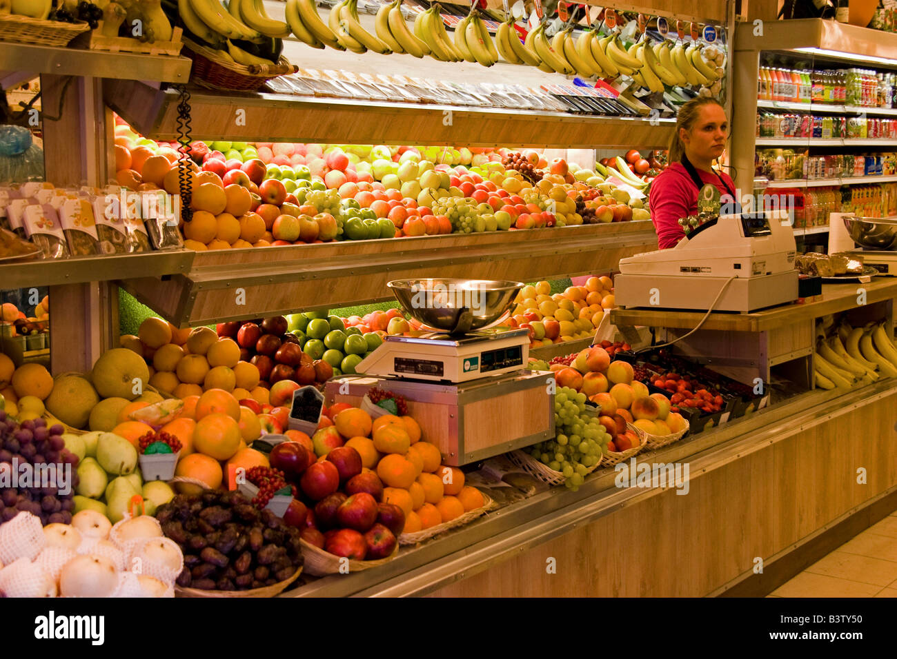A produce shop with colorful fruits and vegtables and a sales girl near ...