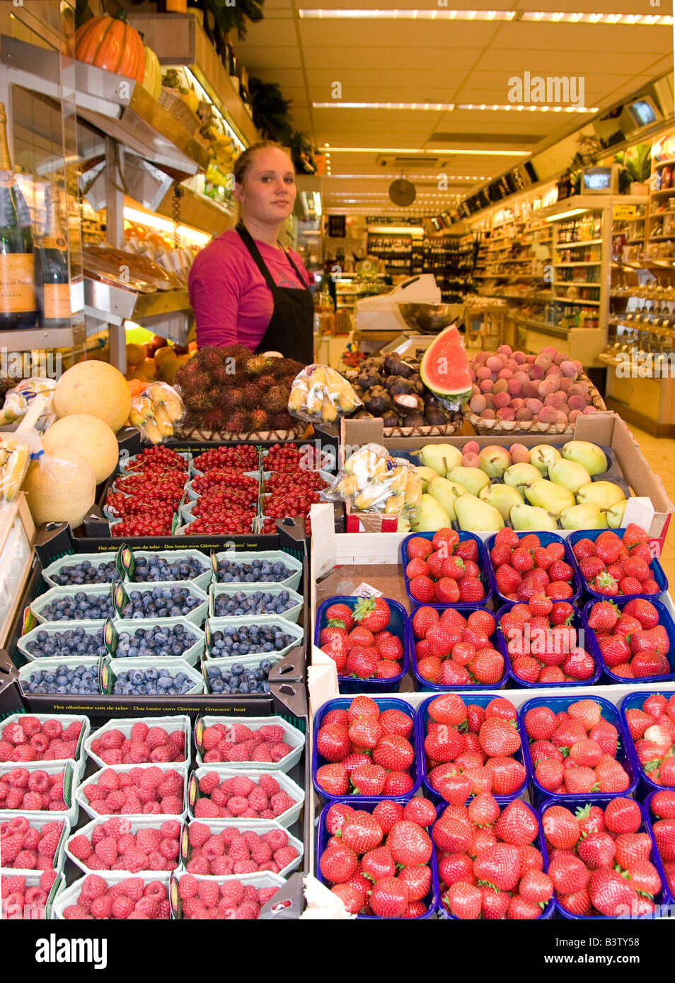 A produce shop with many colorful fruits and a sales girl Stock Photo ...